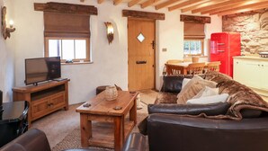 Uma sala de estar aconchegante com teto de madeira, televisão, mesa de jantar e sofá.