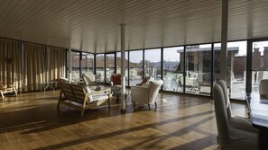 Quarto espaçoso com amplas janelas, piso de madeira e móveis modernos.
