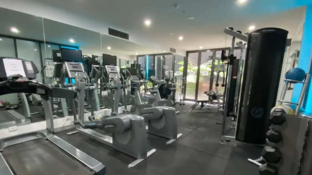 Academia moderna com esteiras, aparelhos de musculação e saco de pancada.
