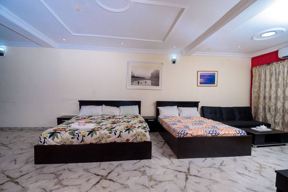 Quarto de hotel com duas camas, piso de mármore, teto com iluminação embutida e um quadro na parede.