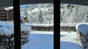 Pátio coberto de neve com vista para uma montanha e edifícios ao fundo.