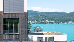 Um edifício moderno com grandes janelas com vista para um lago e colinas arborizadas.