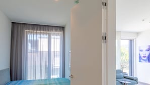 Quarto com cama, porta e vista para uma varanda.