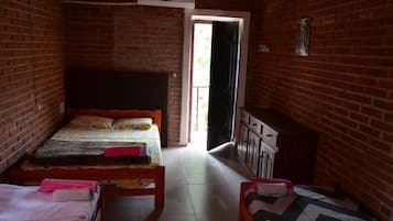 Quarto com duas camas, um guarda-roupa e uma porta que dá para o exterior.