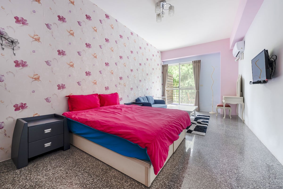 Quarto com cama, mesa de cabeceira, escrivaninha e cadeira.