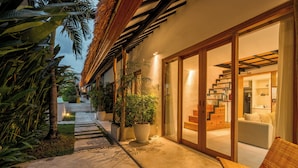 Uma casa moderna com porta de vidro que dá para uma sala de estar, um caminho de concreto e um banco.