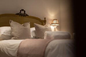 Cama bem arrumada com almofadas, cabeceira, luminária de cabeceira e um enfeite na parede.