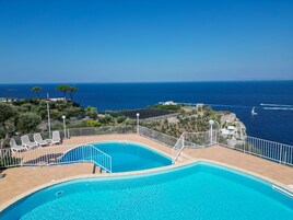 Piscina com vista para o oceano e paisagem costeira.