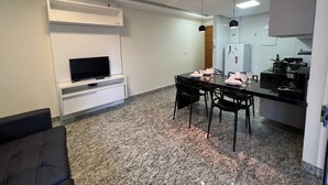 Uma cozinha moderna com área de refeições, bancadas de granito e uma televisão de tela plana.