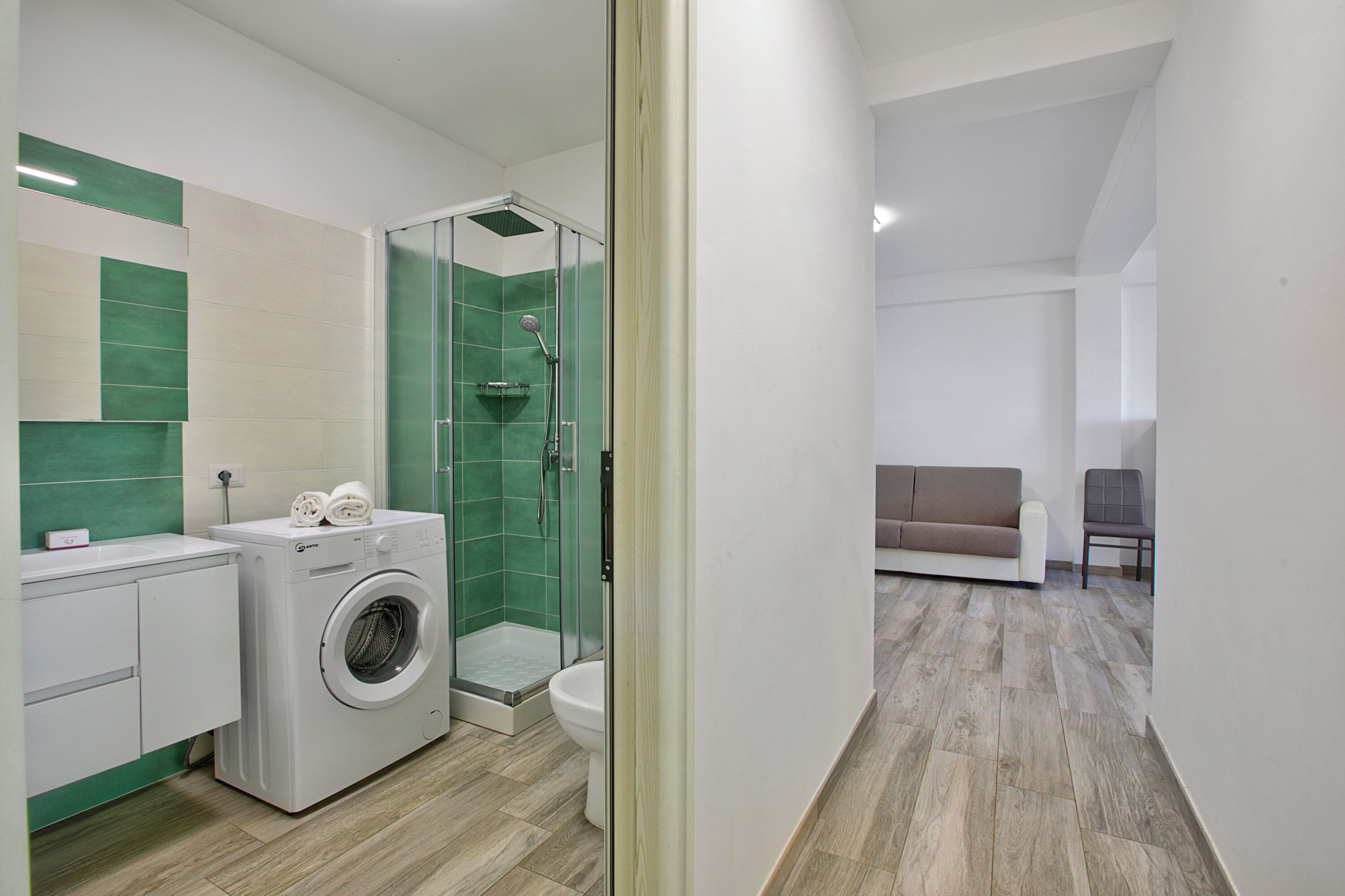 Uma casa de banho moderna com máquina de lavar roupa, cabine de duche envidraçada e sanita.
