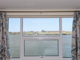 Quarto com uma grande janela com vista para um corpo de água e uma paisagem distante.