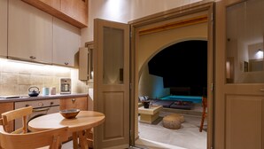 Cozinha moderna com armários de madeira, uma mesa de jantar com cadeiras e vista para uma sala de estar com piscina.