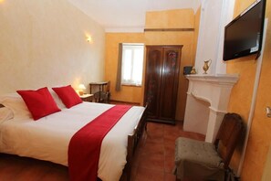 Quarto com cama, poltrona, guarda-roupa, televisão e janela.