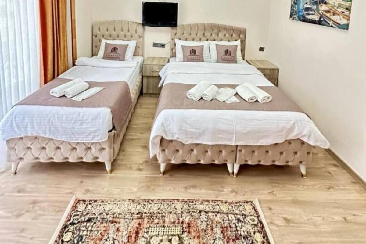 Quarto de hotel com duas camas, televisão de tela plana, um quadro na parede e um tapete estampado.