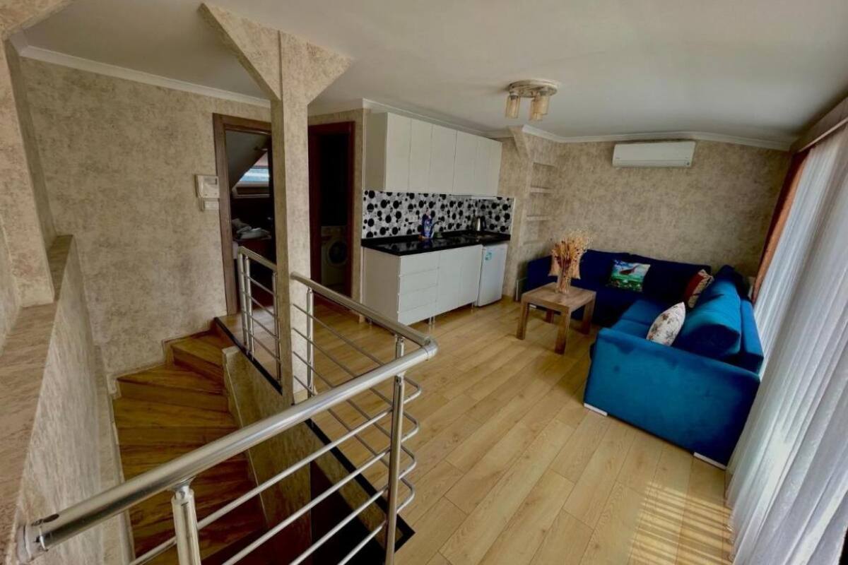 Escada que leva a um patamar com vista para uma cozinha e sala de estar.