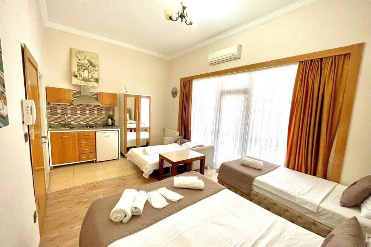 Quarto de hotel com duas camas, uma kitchenette pequena, área de refeições e banheiro.