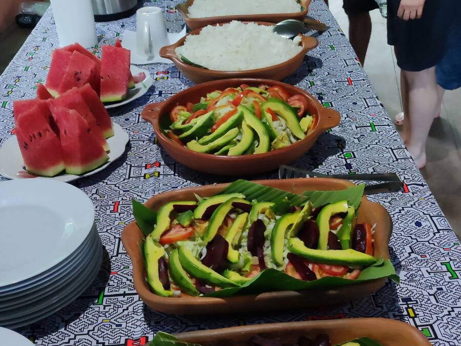 Uma mesa de buffet com diversos pratos, incluindo arroz, frutas e legumes.