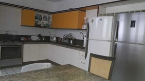 Uma cozinha compacta com armários brancos, uma geladeira de aço inoxidável e um fogão a gás.