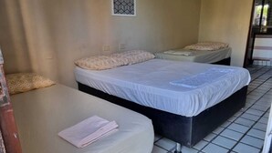 Quarto com duas camas, uma janela pequena e piso de azulejos.