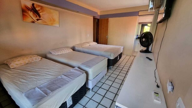 Quarto com duas camas, uma kitchenette pequena e um ventilador de teto.