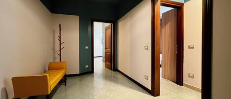 Um corredor com um banco, portas e um aparelho de luz.