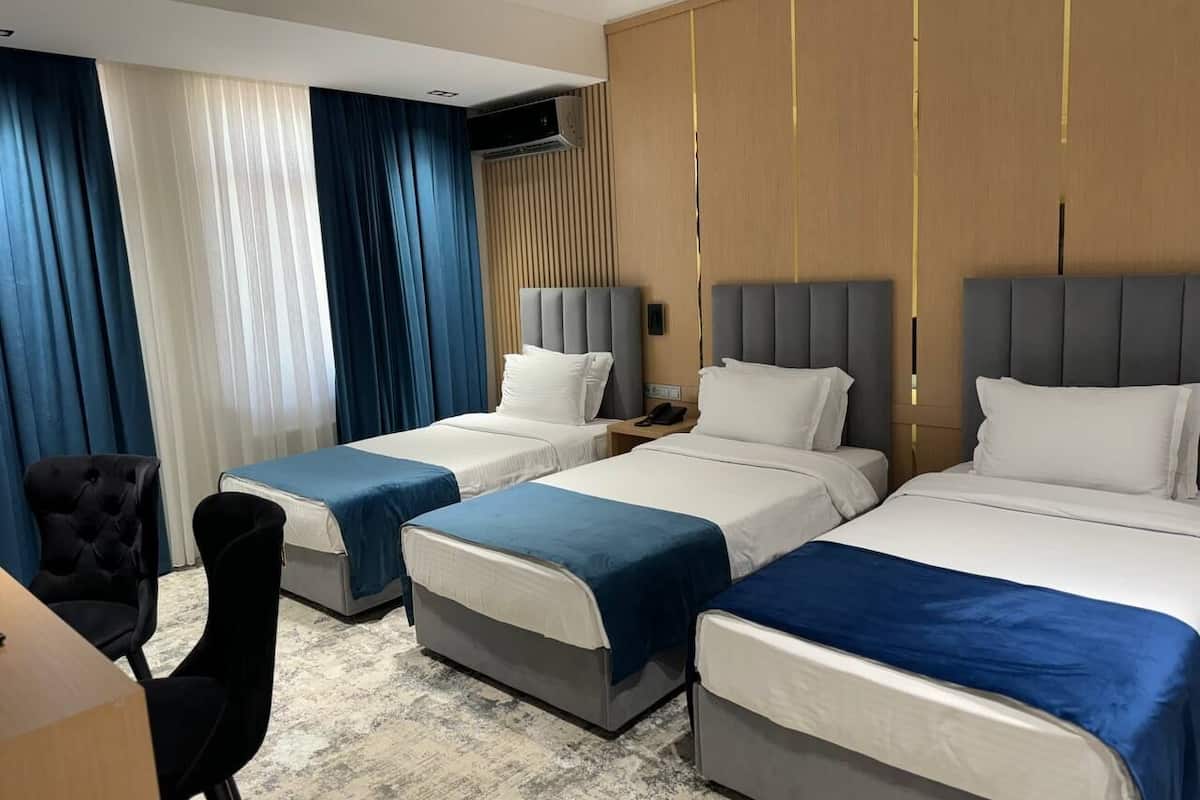 Quarto de hotel com duas camas, uma escrivaninha e uma cadeira.