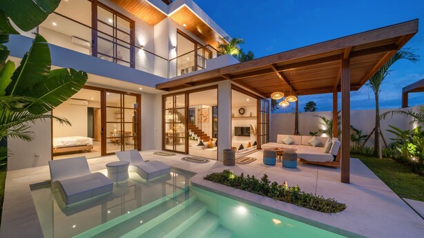 Uma casa moderna de dois andares com piscina envidraçada, área de estar externa e varanda coberta.