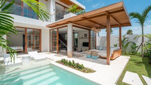 Uma casa moderna de dois andares com piscina, área de estar externa e um alpendre coberto.