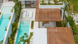 Uma casa moderna de vários andares, com piscina, área de estar externa e paisagismo exuberante.