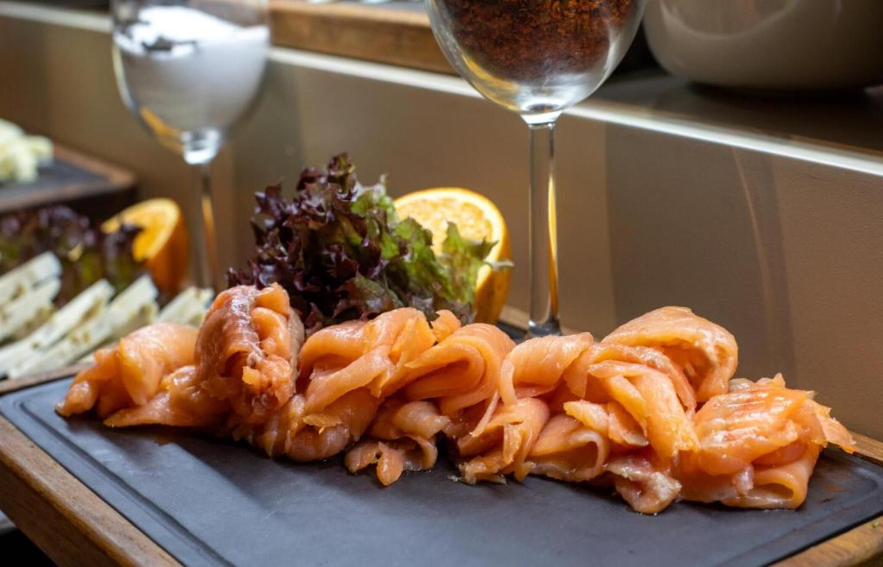 Um prato de salmão defumado com uma taça de vinho branco e uma fatia de limão.