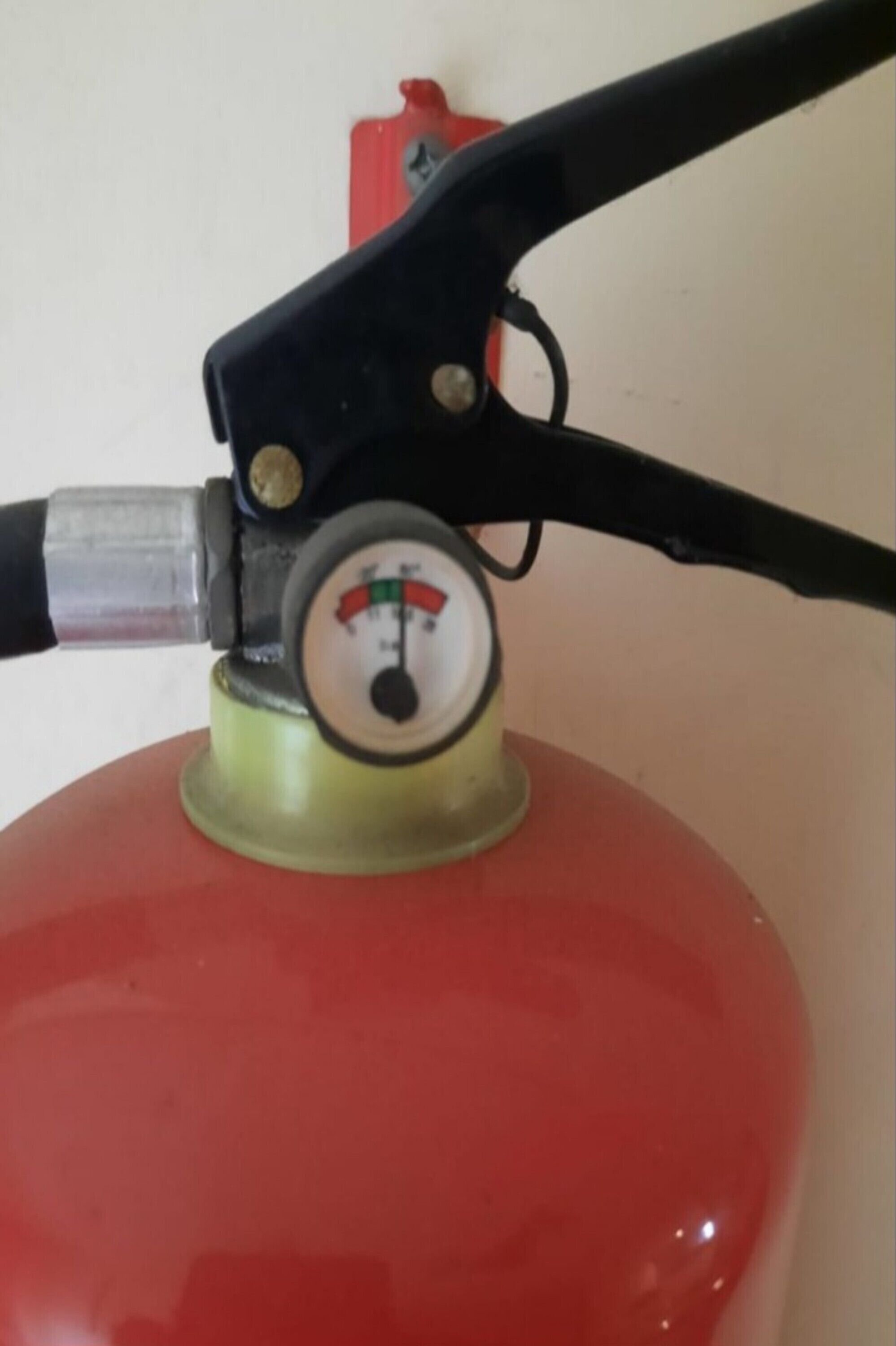 Um extintor de incêndio vermelho com um medidor de pressão e uma alça preta.