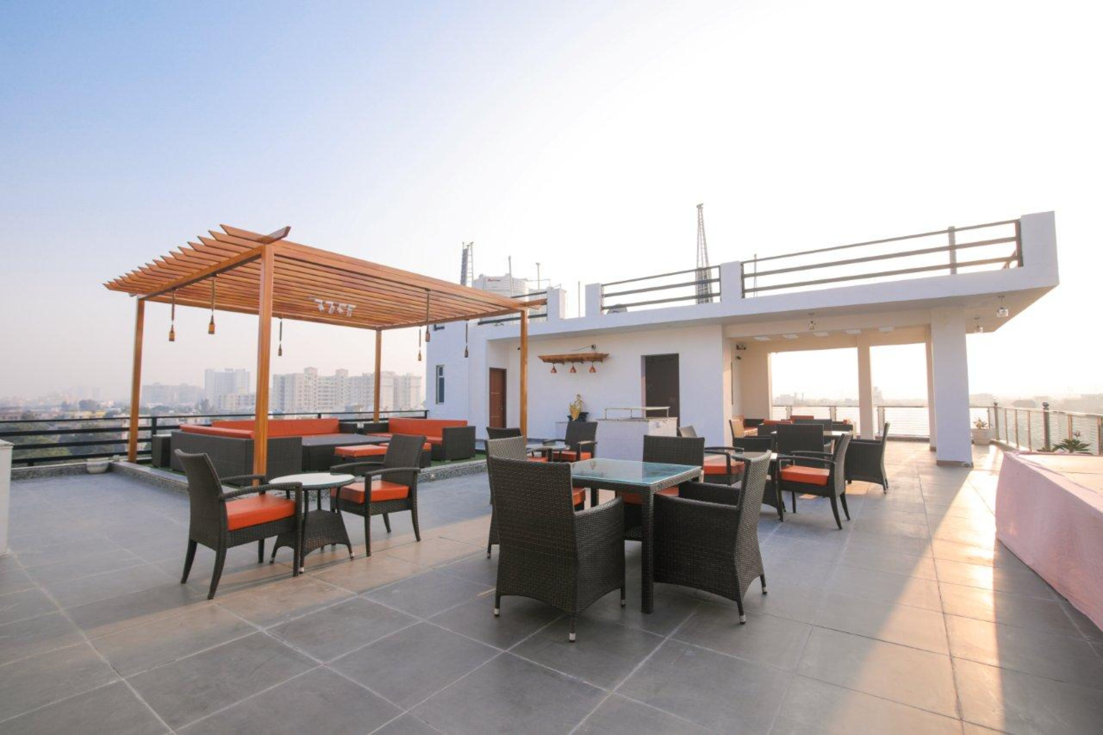 Terraço no telhado com área de estar externa, pérgola e vista para o horizonte da cidade.