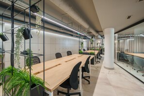 Um espaço de escritório moderno com mesas longas, cadeiras de escritório pretas e plantas em vasos.