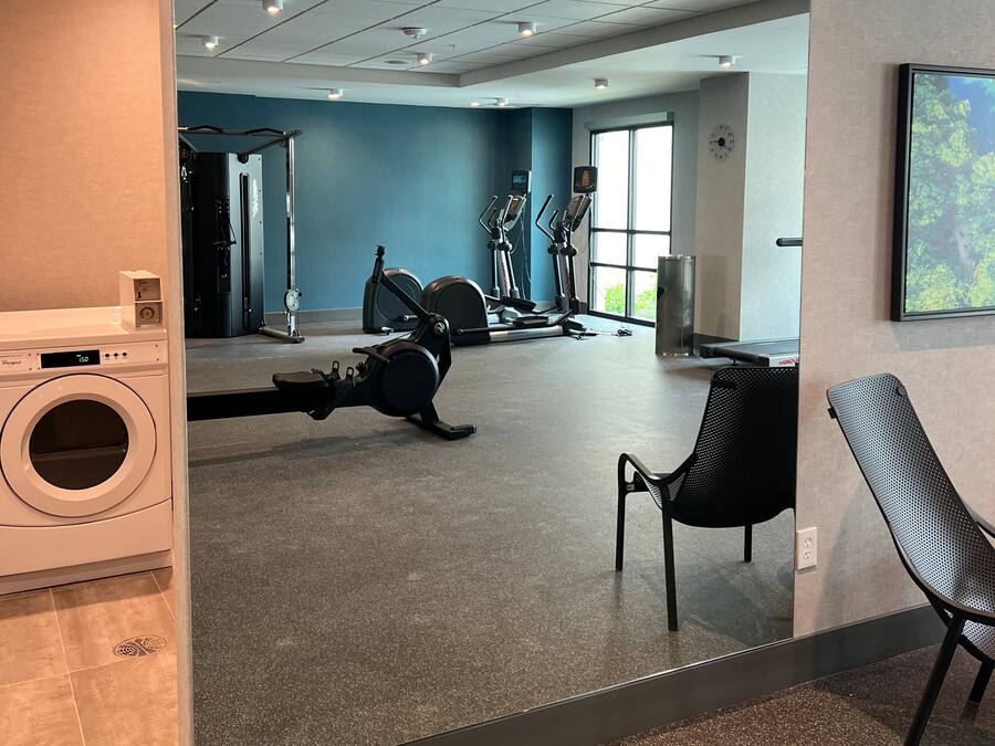 Uma academia com equipamentos de exercícios, um espelho grande e uma janela que oferece luz natural.