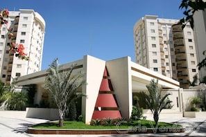Um edifício moderno com estrutura triangular única, cercado por vegetação e palmeiras.