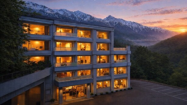 Um hotel com vários andares, varandas, janelas amplas e vista para montanhas cobertas de neve.
