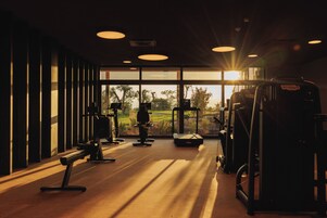 Uma academia com equipamentos de ginástica, janelas amplas e vista para o exterior.