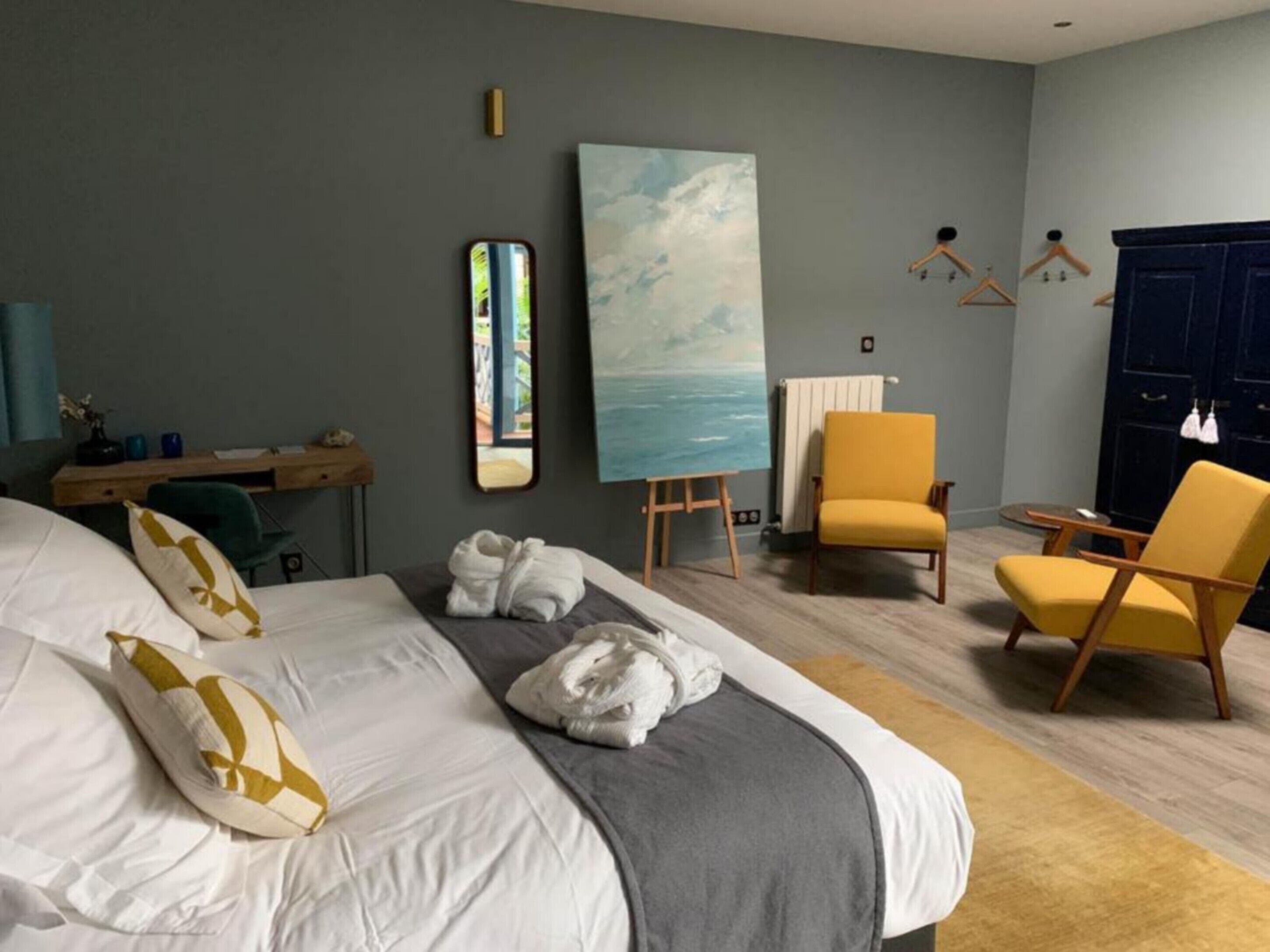 Quarto de hotel moderno com uma cama grande, uma mesa, uma cadeira e um quadro na parede.