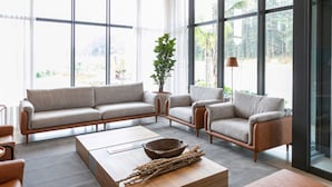 Uma sala de estar moderna com uma janela grande, um sofá, uma mesa de centro e um banquinho.