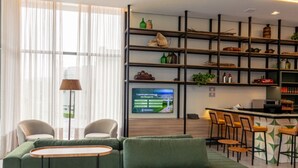 Uma sala de estar moderna com um sofá seccional, uma mesa de madeira pequena e um espaço bar com banquetas.