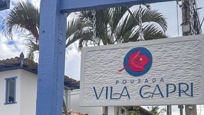 Placa de Vila Capri com logotipo, parede branca e detalhes em azul.