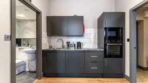Cozinha moderna com armários escuros, micro-ondas e cafeteira sobre a bancada.