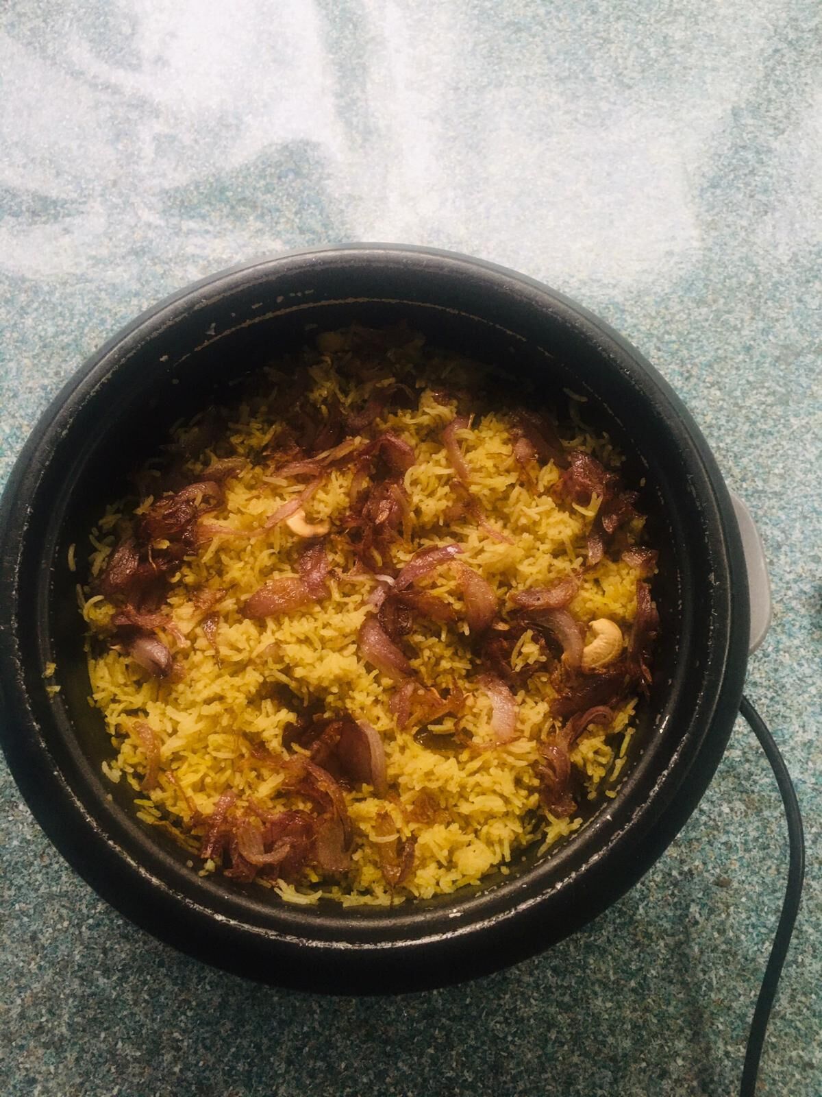 Uma tigela de arroz amarelo com pedaços de carne e cebola.