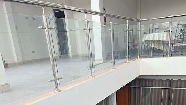 Interior com vários níveis, guarda-corpos de vidro e vista para uma área de refeições abaixo.