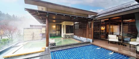 Uma área de piscina moderna ao ar livre, com hidromassagem, deck de madeira e espaço para sentar.