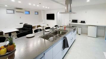 Uma cozinha moderna com ilha central, micro-ondas embutido e frigorífico pequeno.