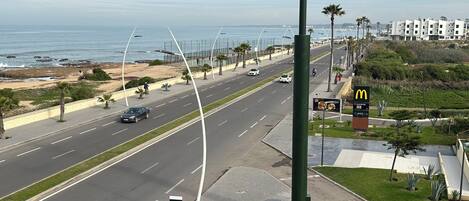 Uma estrada costeira com um letreiro do McDonald's, sinalização de estacionamento e uma passarela para pedestres.