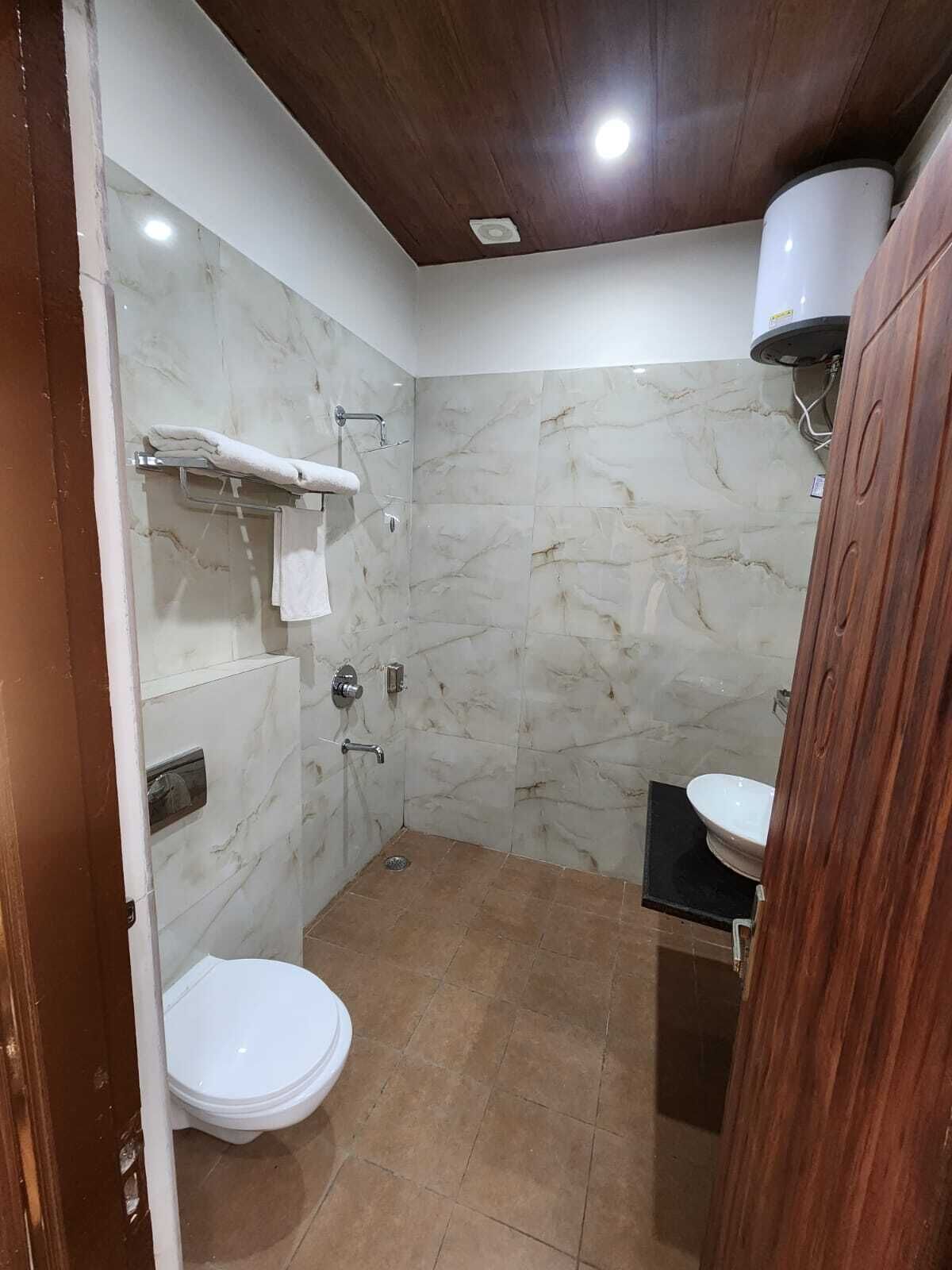 Uma casa de banho com sanita branca, chuveiro e lavatório.