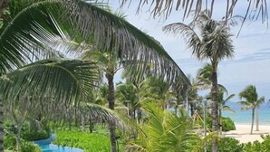 Uma área de piscina com um recurso aquático de água azul cristalina, rodeada por vegetação exuberante e palmeiras.