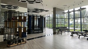 Uma academia com piso de madeira, equipamentos de exercício e amplas janelas com vista para o exterior.